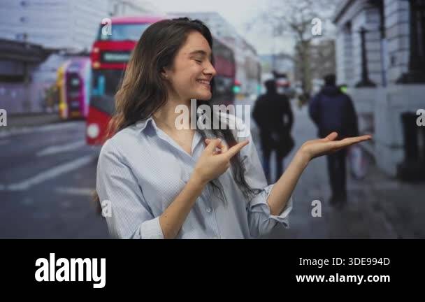 Woman smiling and pointing finger at open palm on city street with red ...