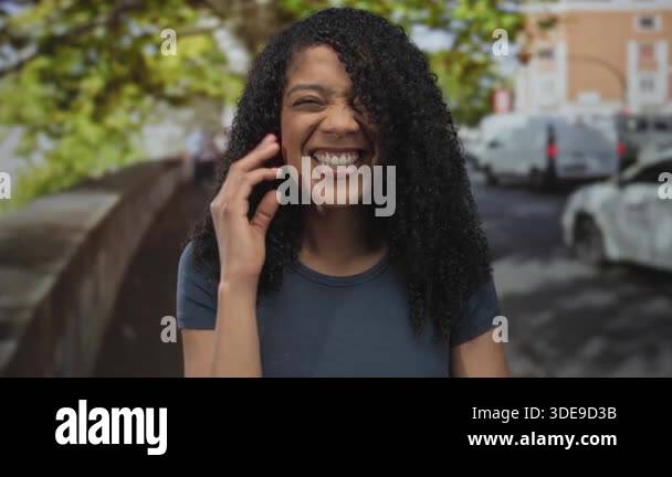 African american woman with curly hair laughing and gestures open hands ...