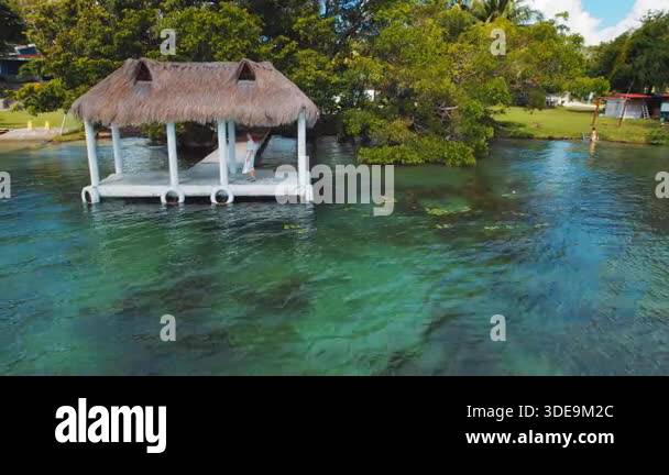 Woman walking on dock above crystal clear water of Bacalar Lagoon ...