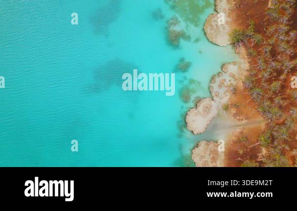 Aerial view of turquoise lagoon meeting dry red shoreline in tropical ...