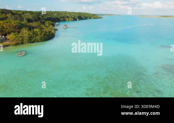 Calm lagoon with clear turquoise water near lush forest edge in Bacalar ...
