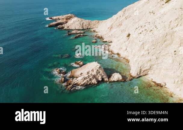 Rock formation rising from turquoise water by white cliff coastline in ...