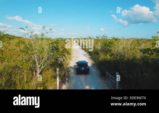 Car driving along dirt road through tropical vegetation in Bacalar ...
