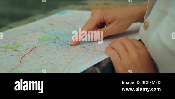 Woman pointing at a location on a paper map while exploring a city in ...