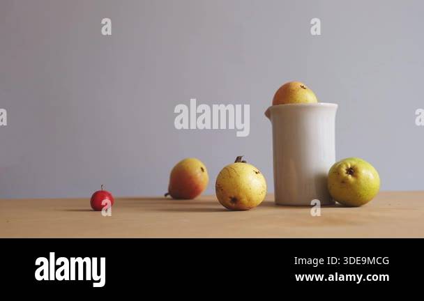 A minimal still life composition featuring scattered pears and a small ...