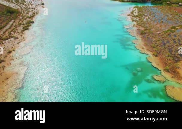 Drone flying over turquoise Bacalar lagoon by vegetation and shallow ...