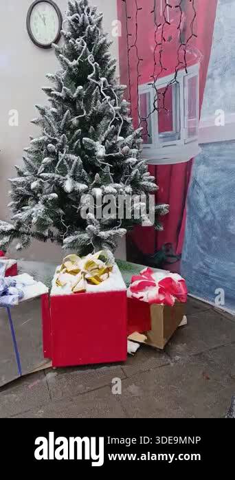 A snow-covered green Christmas tree. Bright gifts for the family lie ...