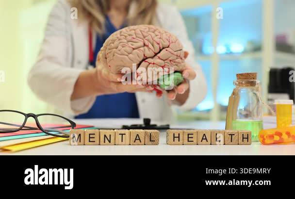 Wooden blocks on desk spell words Mental Health by brain model. Doctor ...