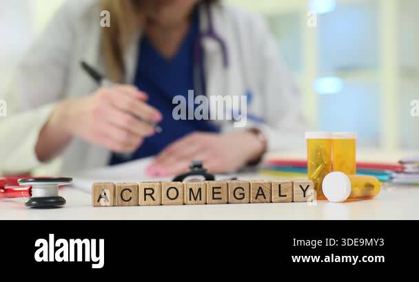 Wooden blocks on medical desk spell word Acromegaly beside pills ...