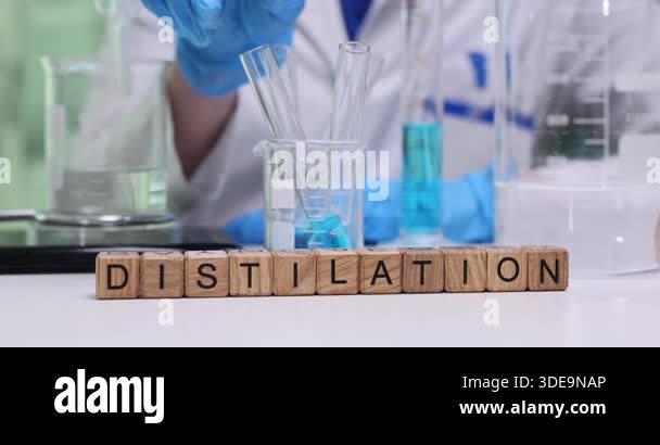 Wooden blocks on lab bench spell word Distillation near blue liquids ...