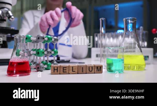 Wooden blocks on table spell word Helium beside colorful reagents ...