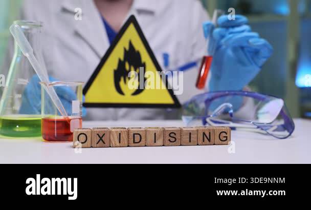 Laboratory technician holds test tube and fire warning sign to ...