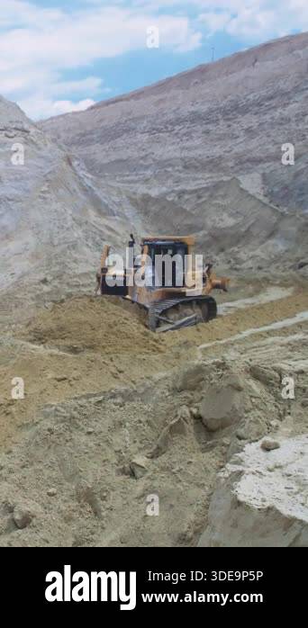 bulldozer grading sandy quarry slopes, tracked dozer pushing large ...