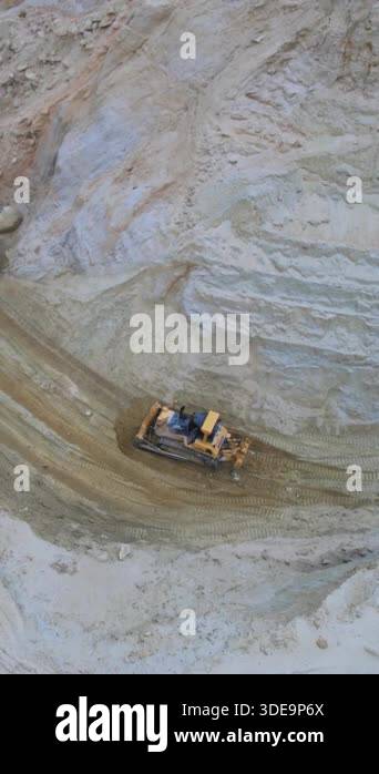 bulldozer grading sandy quarry slopes, tracked dozer pushing large ...