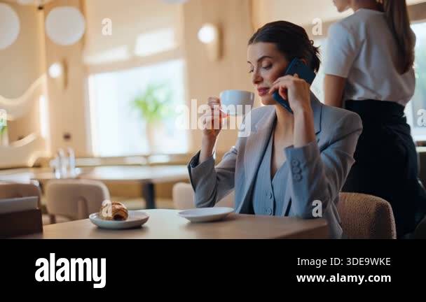 Confident manager calling in cafeteria sitting small table alone ...