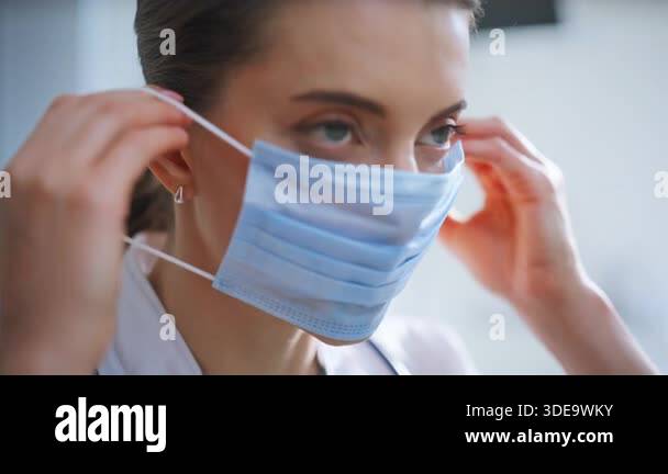 Doctor woman putting protective mask on face in clinic portrait ...