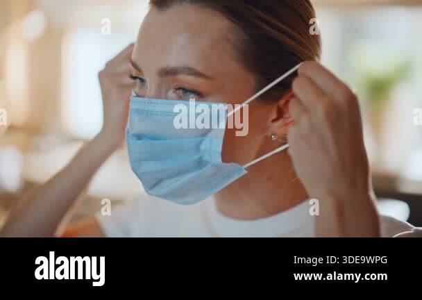 Lady waitress putting medical protection on face in light workplace ...