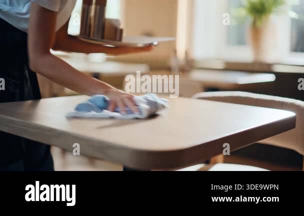 Waitress wiping table restaurant closeup. Serious female worker ...