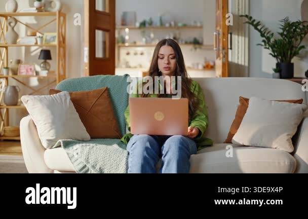 Focused lady surfing laptop internet sitting at cozy apartment couch ...