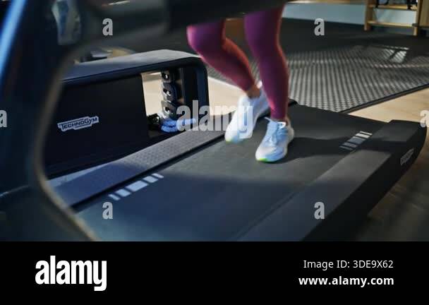 Energetic runner training on jogging machine wearing sportswear closeup ...