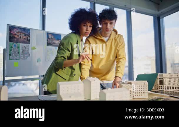 Two realtors discussing buildings models at modern meeting room ...
