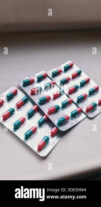 High-angle shot of three silver blister packs containing red and blue ...