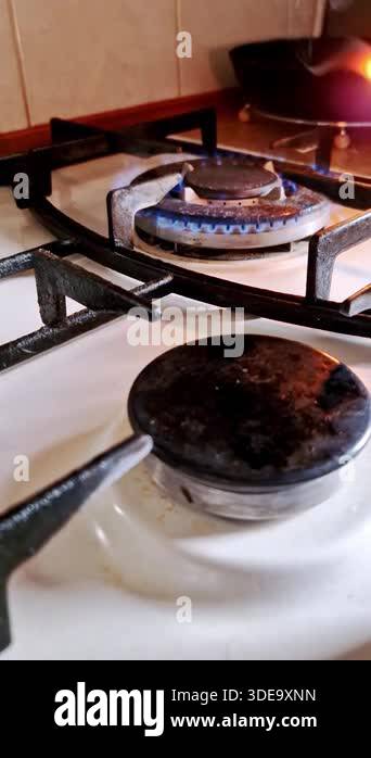 Vertical, Close-up of a match igniting a gas stove burner on a white ...