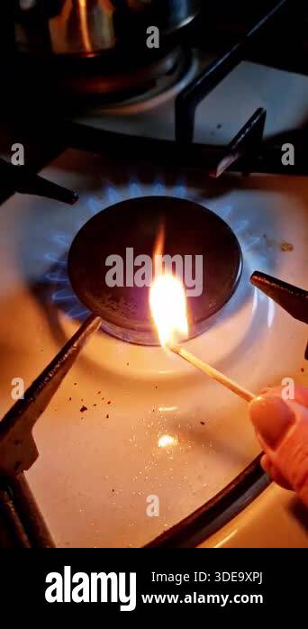 Close-up view of a hand holding a burning wooden matchstick next to a ...