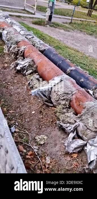 Two large industrial pipes lie at ground level. One brown and one black ...