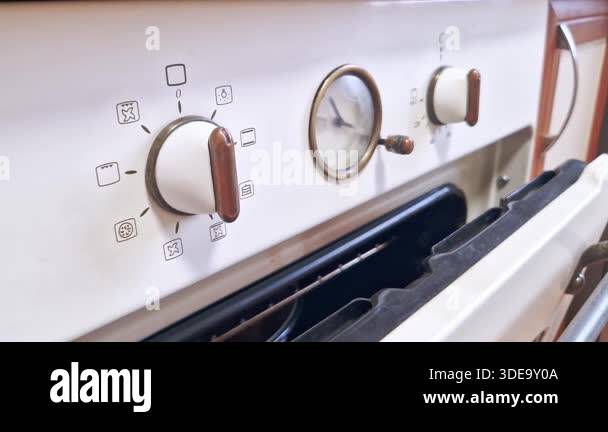 Close-up shot of a white vintage oven control panel. Three brass ...
