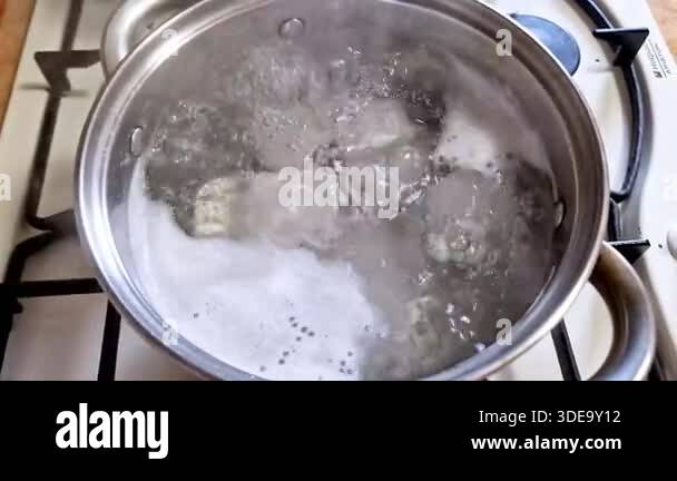 Top down view of water rapidly boiling to cook eggs inside a stainless ...