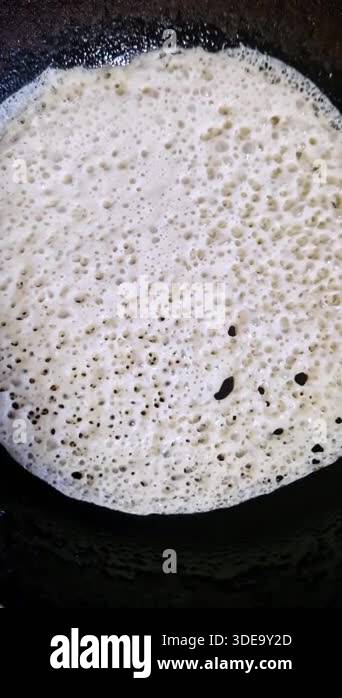 Vertical, macro top-down view of yeast pancake batter cooking in a hot ...