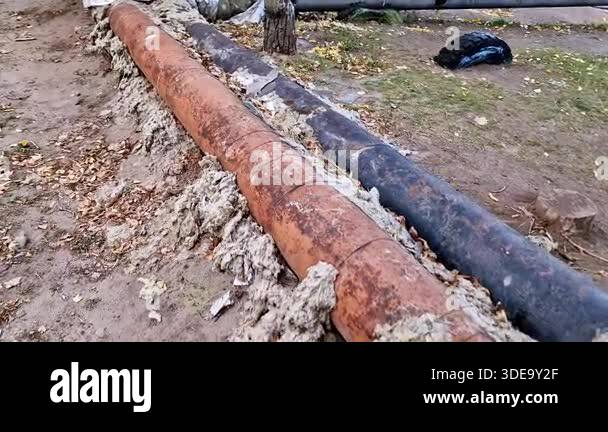 Ground level perspective of three rusted metal pipes with exposed ...