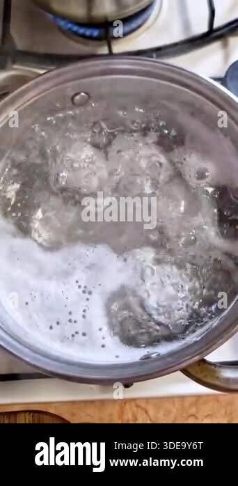 Top down view of water rapidly boiling to cook eggs inside a stainless ...