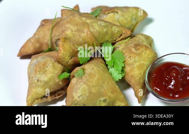 Indian samosa served with tomato sauce, green chili and coriander ...
