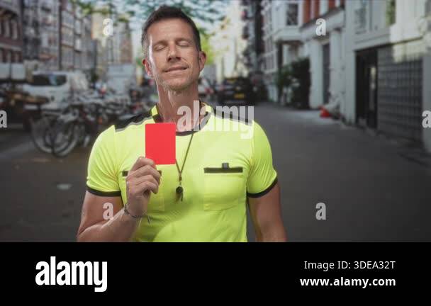 Referee man in fluorescent yellow shirt holding a red card and whistle ...