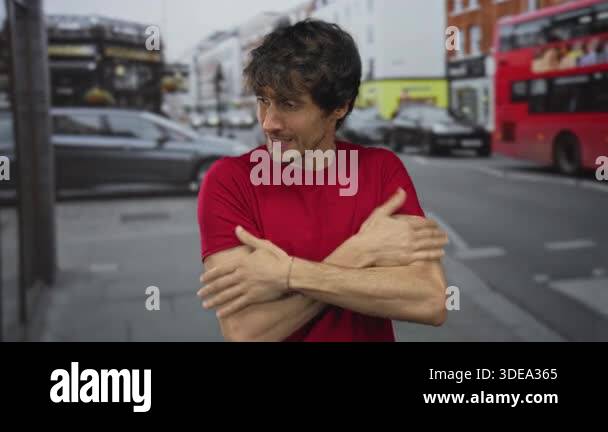 Young man in red t-shirt claps hands on busy city street with tense ...