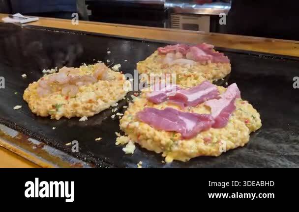 Chef cooking okonomiyaki Japanese style pizza on hot plate Osaka street ...
