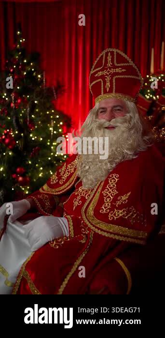 Smiling Saint Nicholas seated in ornate red robe with Christmas tree ...