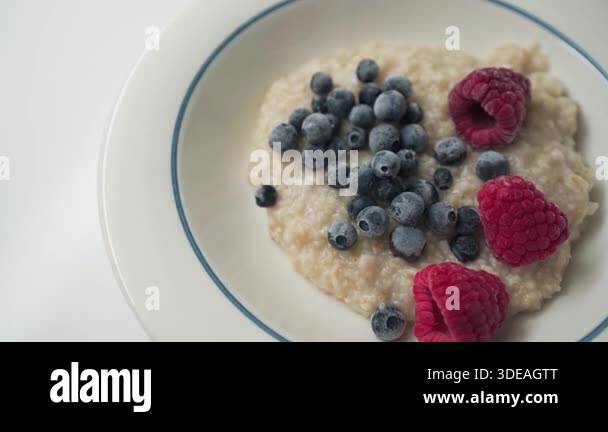 A panning shot shows a bowl of Finnish oat porridge topped with ...