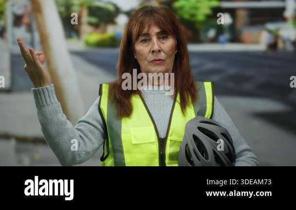 Hispanic senior woman meditating outdoors in city street, holding a ...