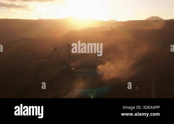 Aerial flyover of an active open-pit coal mine against backlight at ...