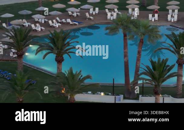 High-angle aerial view of a luxury resort swimming pool at dusk ...