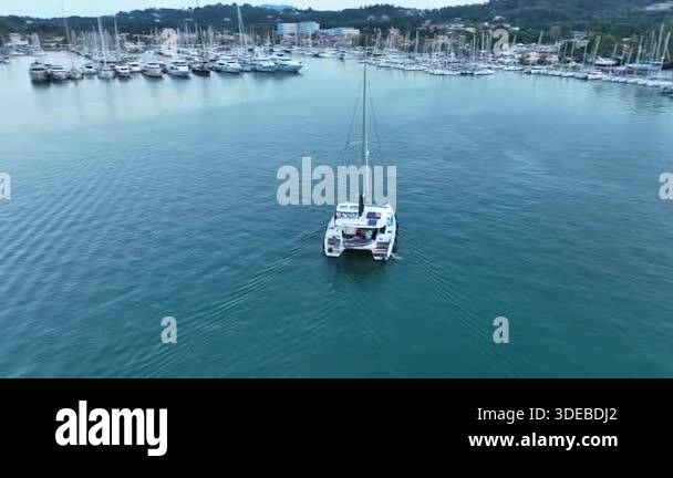 Front aerial view of modern white catamaran yacht sailing slowly in ...