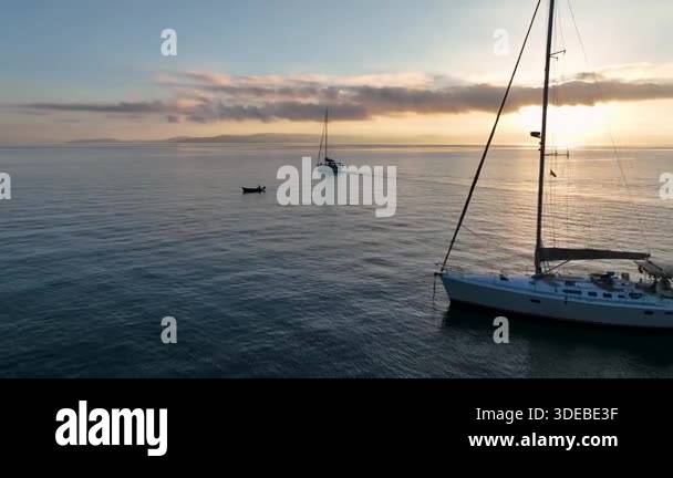 Close-up aerial view of a luxury sailboat anchored at sunset. Crew ...