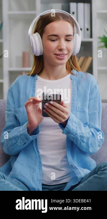 Young woman using phone to browse social media with headphones while ...