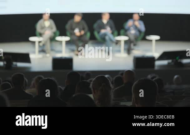 Panel discussion with four speakers on stage engages audience during ...