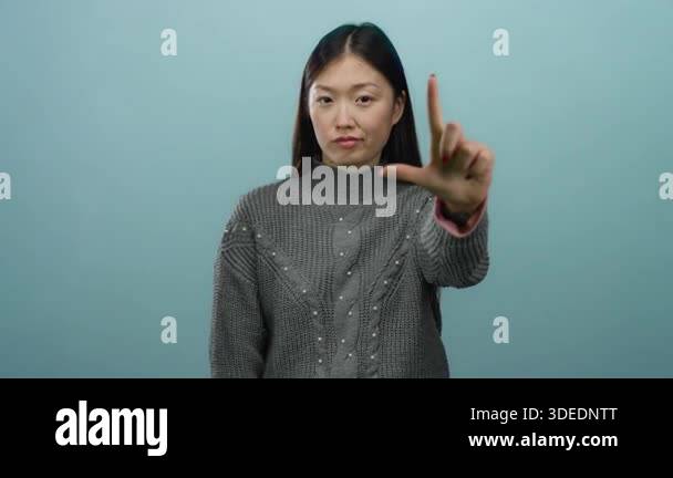 Woman making loser gesture over blue background, emphasizing youthful ...