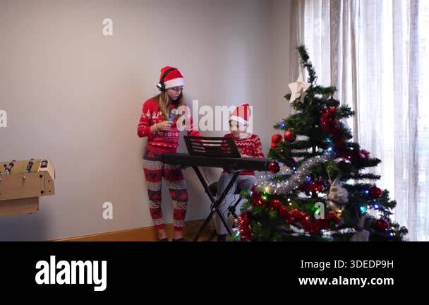 Siblings wearing matching pajamas and santa hats celebrate christmas ...