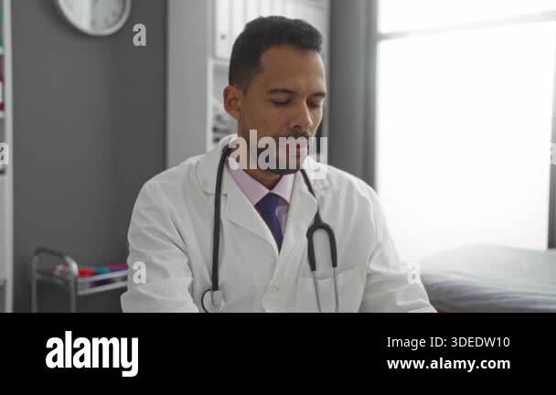 Doctor working in a clinic room with a laptop, wearing a white coat and ...